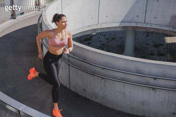 Young woman taking up fitness outdoors, running on round elevated ...