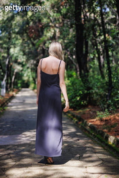 Rear view on beautiful blonde woman standing in the shade in natural ...
