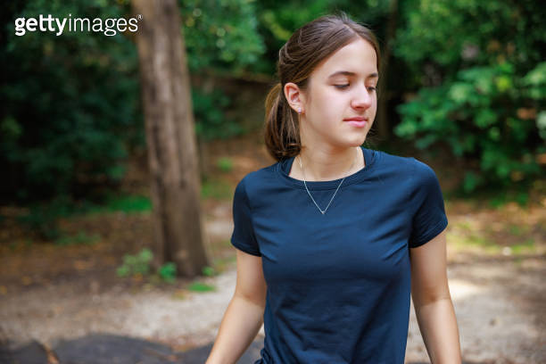Portrait of cute teenage girl standing in the nature park and looking ...