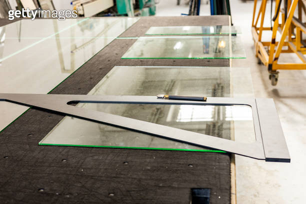 Glass factory. A sheet of glass on a cutting table and tools for ...
