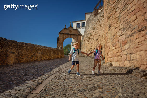 Happy children with backpack run paved street of Ronda, Spain 이미지 ...