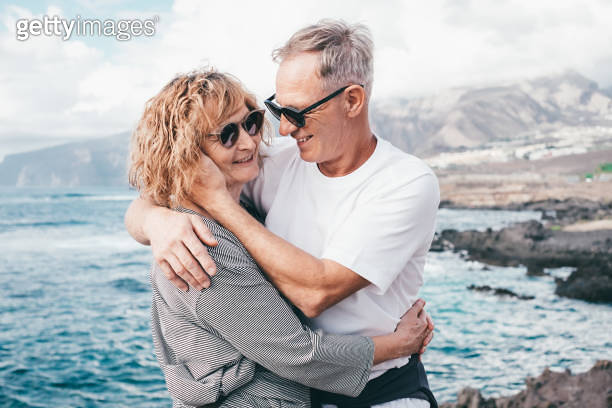 Carefree bonding senior couple embrace on the seashore enjoying sunset ...