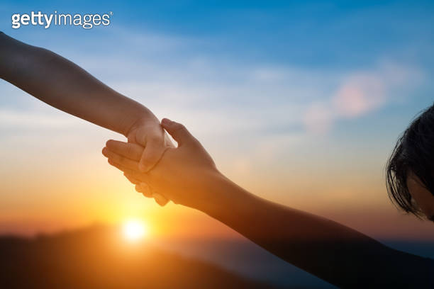 Silhouette of reaching, giving a helping hand, hope and support each other over blur sunset sky ...