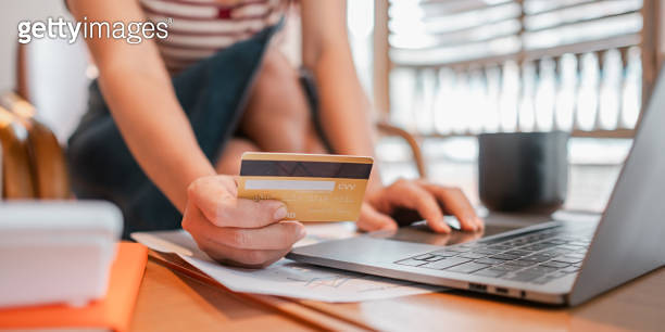 A woman is using a laptop to pay for something with a credit card. She ...