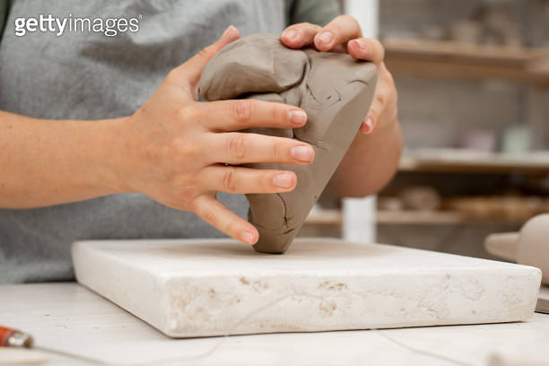 Wedging the clay before starting making a pottery project to create ...