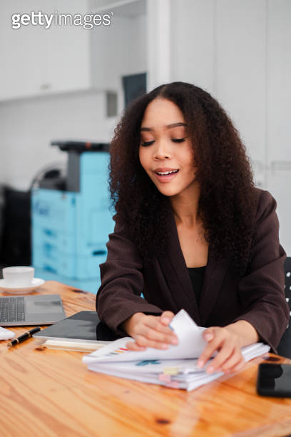 Focused African American woman sorting through paperwork at her office ...