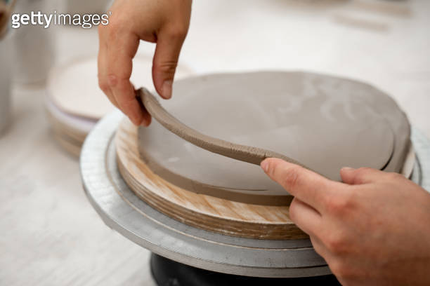 Girl is modeling clay into a round form. Using a sharp pottery carving ...