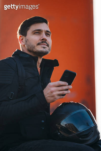 Portrait of a Handsome Smiling Motorcycle Rider Sitting and Using His ...