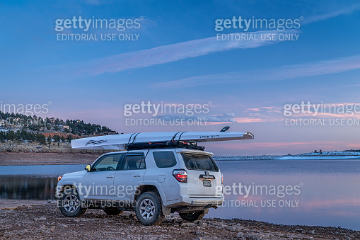 Toyota 4Runner SUV with Liteboat rowing shell on roof racks on a shore ...