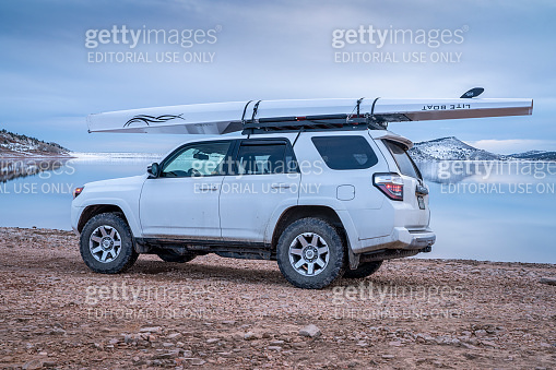 Toyota 4Runner SUV with Liteboat rowing shell on roof racks on a shore ...