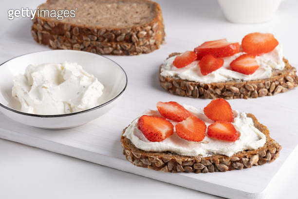 Rye bread with cream cheese and strawberry on a white table. Whole ...