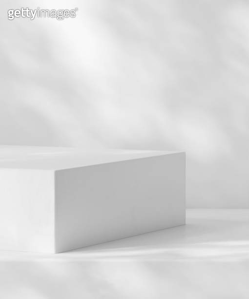 Modern white geometric cuboid podium in dappled sunlight, leaf foliage ...