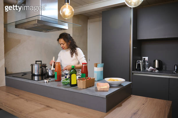 Beautiful woman cooking family dinner at modern minimalist home kitchen ...
