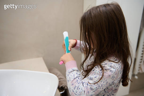 Caucasian little kid girl squeezing toothpaste on her pink toothbrush ...