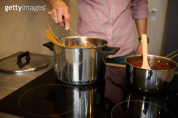 Male chef cook preparing Italian pasta at home. Cropped view of a young ...