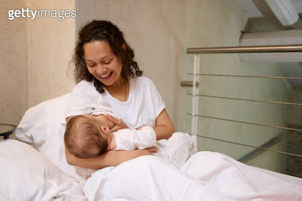 Happy mother smiles breastfeeding newborn baby, expresses positive ...