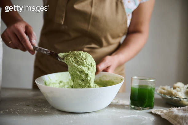 Close-up housewife's hands kneading dough with wooden spoon in the ...