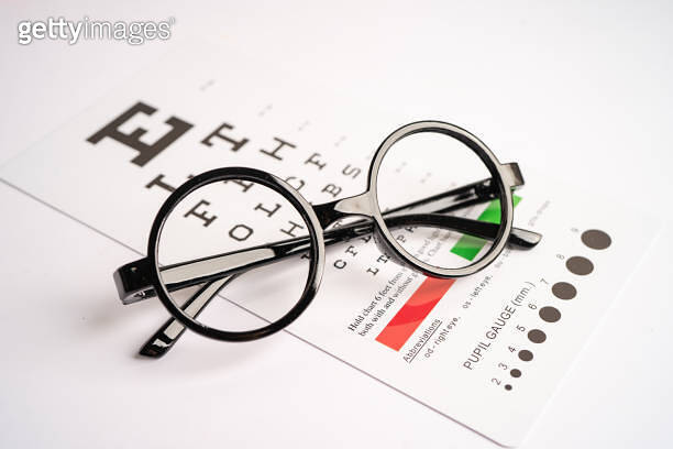 Glasses on eye testing exam chart to check eyesight accuracy of reading ...