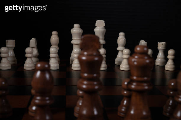 Close up of chess pieces on a chess board. opponent pieces in focus in ...