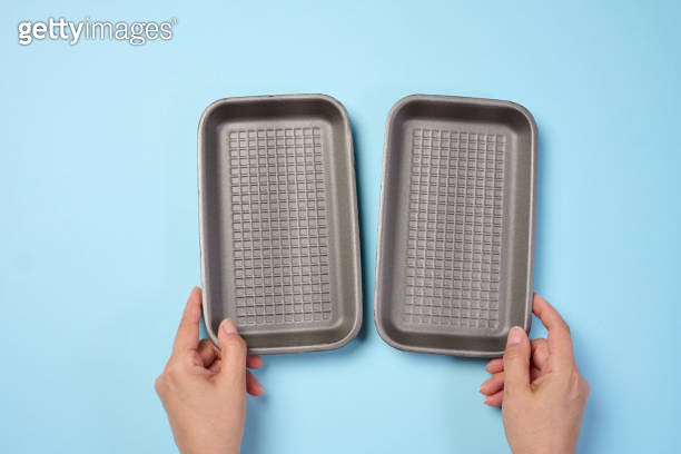 Hand holds black disposable polystyrene foam rectangular plate for ...