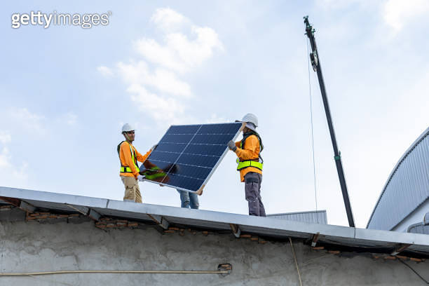 Technicians Install photovoltaic solar modules on roof of factory ...