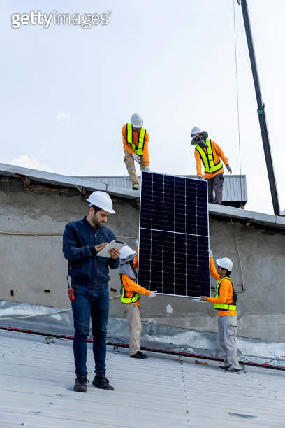 Technicians Install photovoltaic solar modules on roof of factory ...