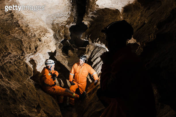 Three men, strong physique, explore the cave. Men dressed in special ...