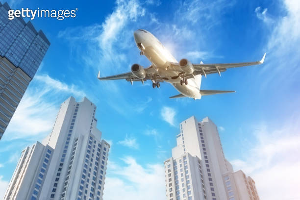Airplane flying above glass office buildings. Look up into the sky. 이미지 ...