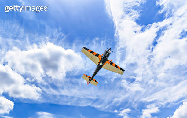 Aerobatic plane (aerodyne), in flight under a blue sky with white ...