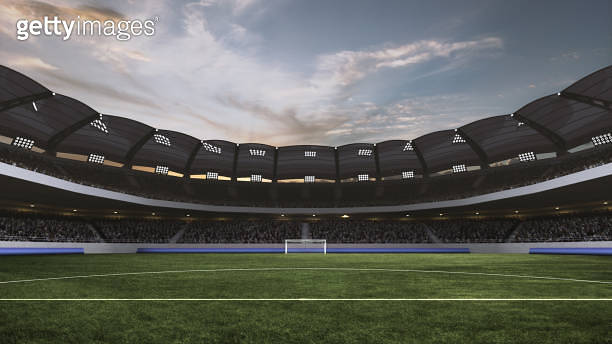 Large empty soccer stadium with green field surrounded stages filled of ...