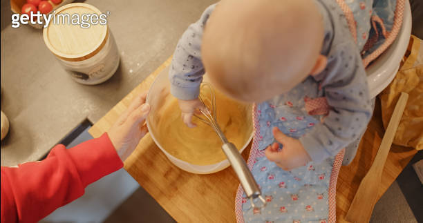 Mother and her little baby cooking food together at home. Mom's little ...
