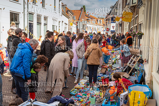 eople walk through the flea market on King's Day in the city of ...