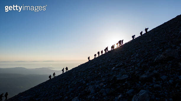 Professional crowded team of mountaineers are walking on sloping ...