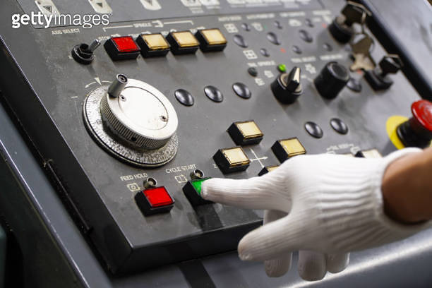 machine operator presses the green start button on the CNC machine's ...