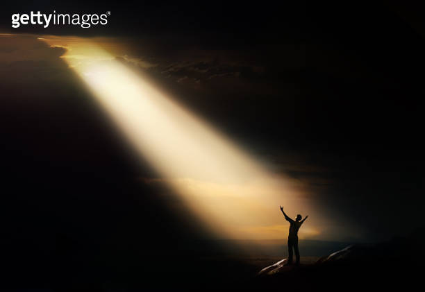 A bright light shines through the clouds and a person praying, shouting ...