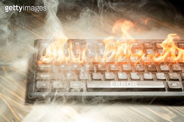 Computer keyboard burned with flame and smokes on wooden desk. 이미지 ...