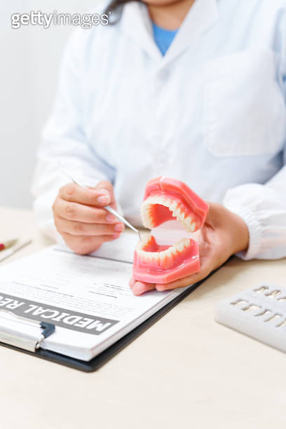 A dentist works at a desk with a tooth model, demonstrating dental care ...