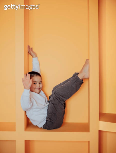 With mischievous grin, boy enjoys his personal hideaway in orange cubby ...