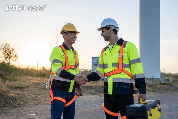 Technicians man making handshake while work in the wind turbines field ...