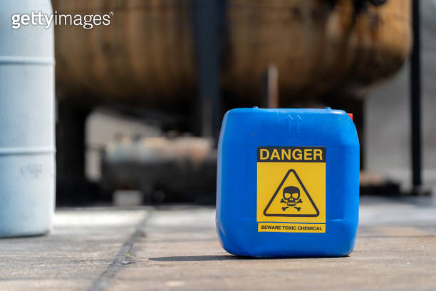 A blue gallon of hazard chemicals rests on the floor of a chemical ...