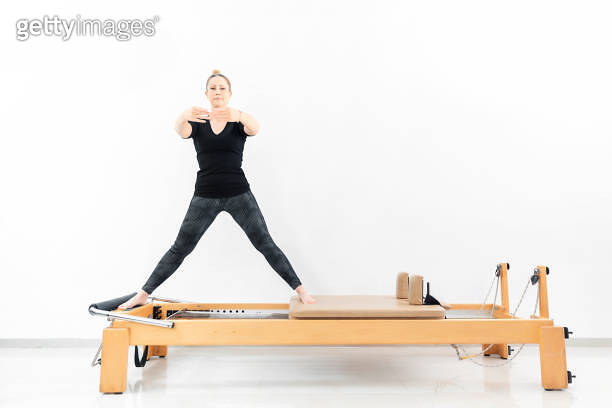 Pilates on reformer machine - a woman does an exercise Side Split Pick ...