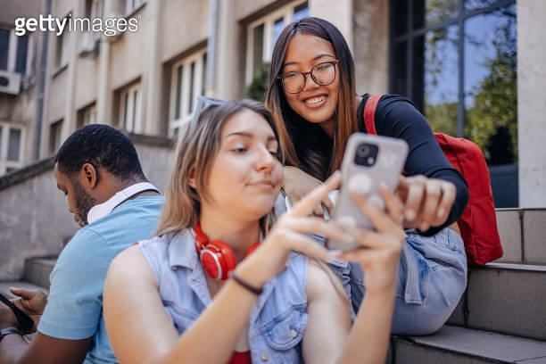 Multiracial group of students sitting in front of University after ...