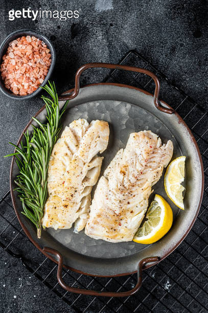 Roast Fillets of codfish, cooked cod fish meat. Black background. Top ...