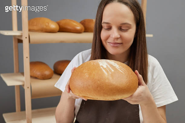 Satisfied delighted woman professional baker smelling freshly baked ...