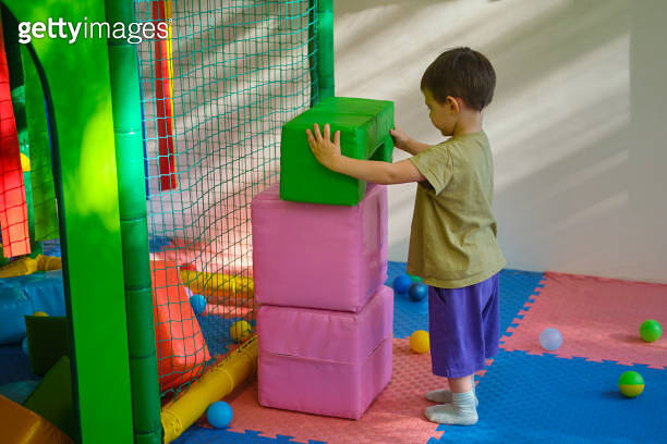 Child stacking soft blocks in indoor playground. Indoor playground ...