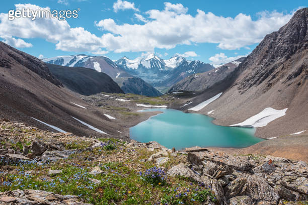 Most beautiful turquoise alpine lake among sheer crags against snow ...