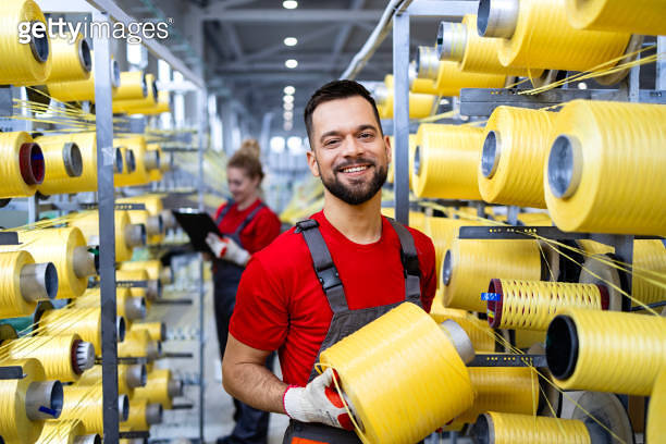 Portrait of textile industry worker holding thread spool by knitting ...
