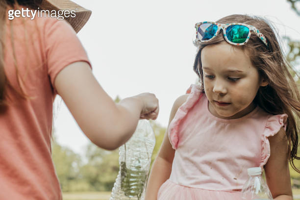 Little girls catch ladybugs together in water bottle while exploring ...