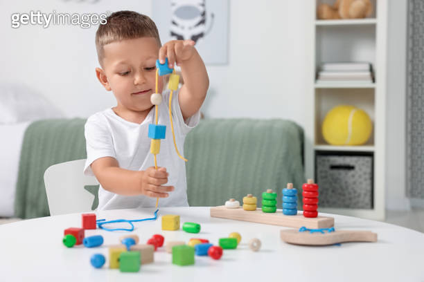 Motor skills development. Little boy playing with wooden pieces and ...