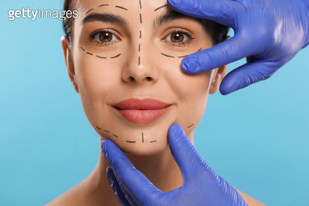 Doctor checking marks on woman's face for cosmetic surgery operation ...